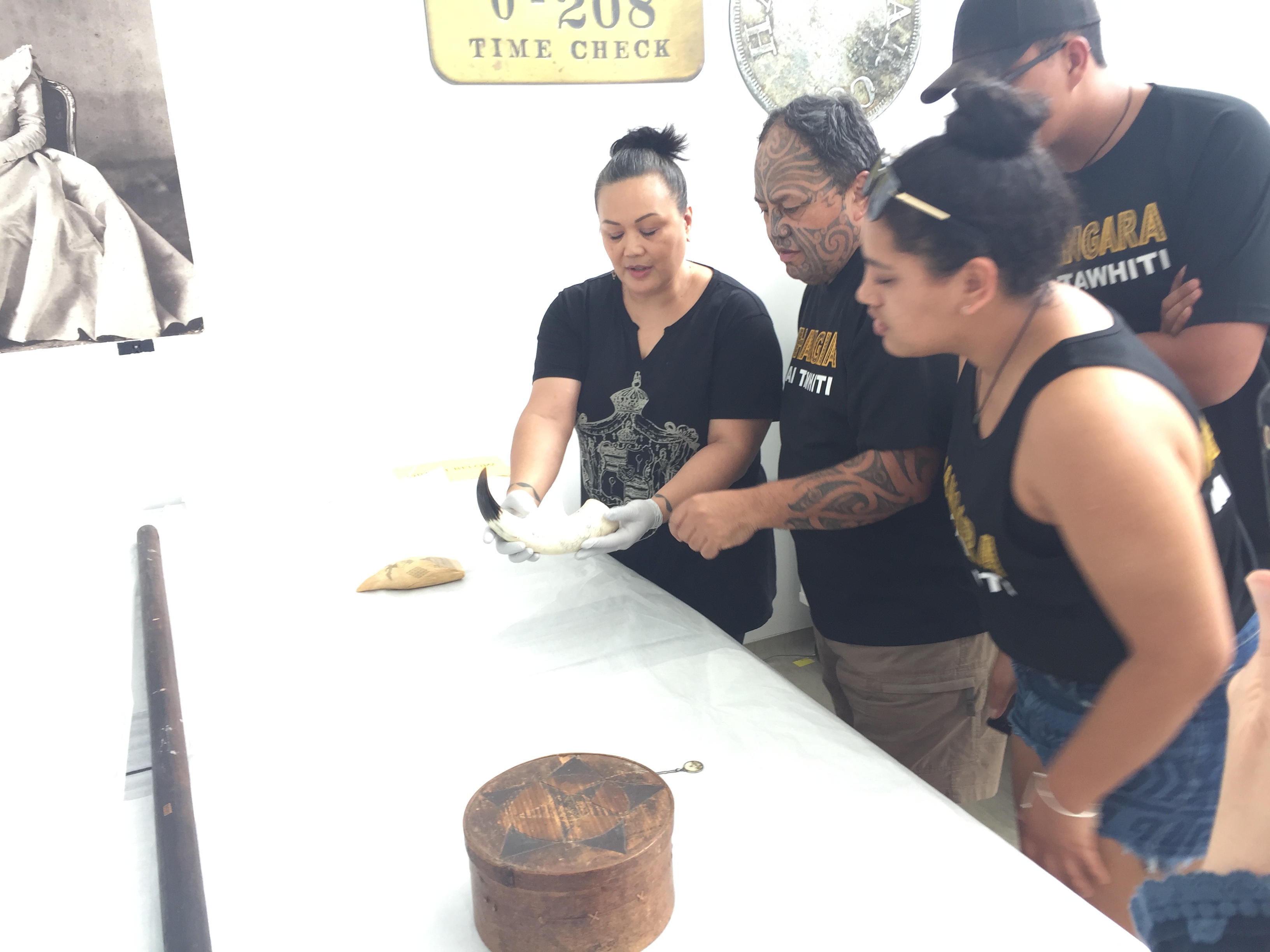 Wayne Ngata and family view a scrimshaw carving depicting Aotearoa